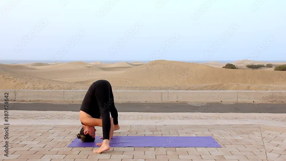 Female yogi goes from headstand to jump back by Maspalomas sand dunes ...