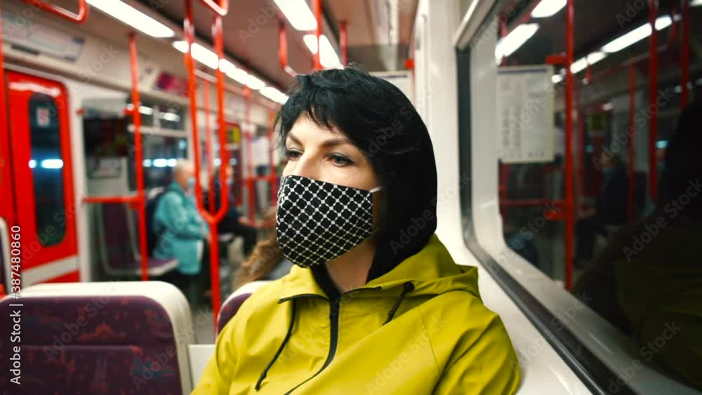 A woman in a mask on her face rides a subway train. He looks around ...