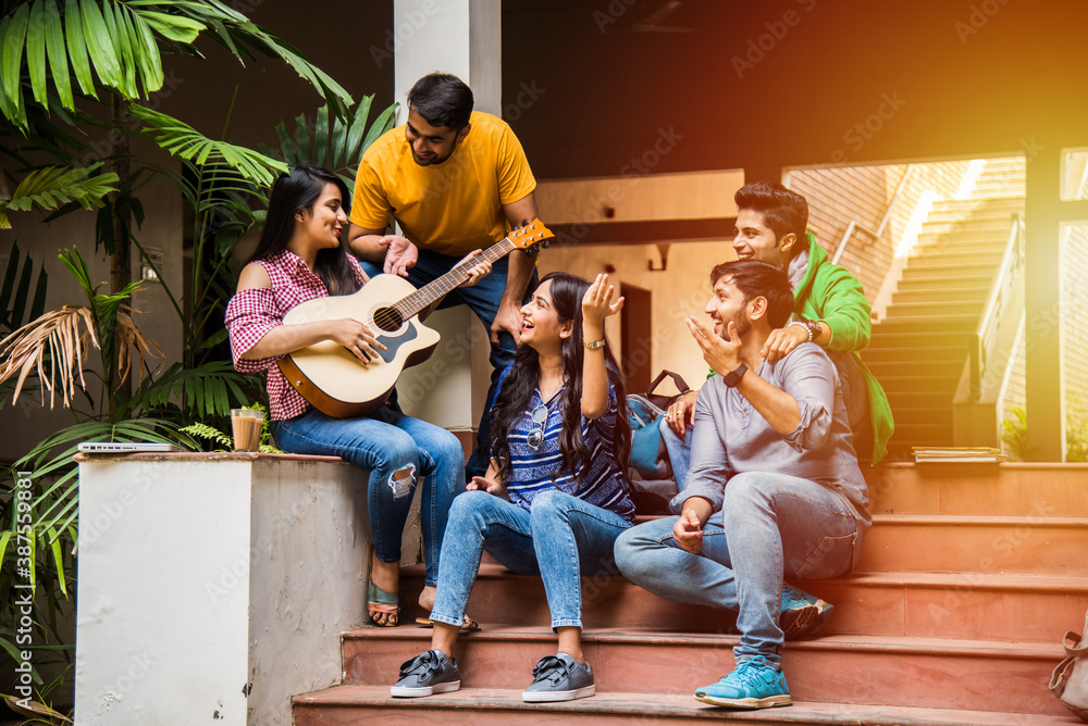 Indian asian university student singing song with guitar in college ...