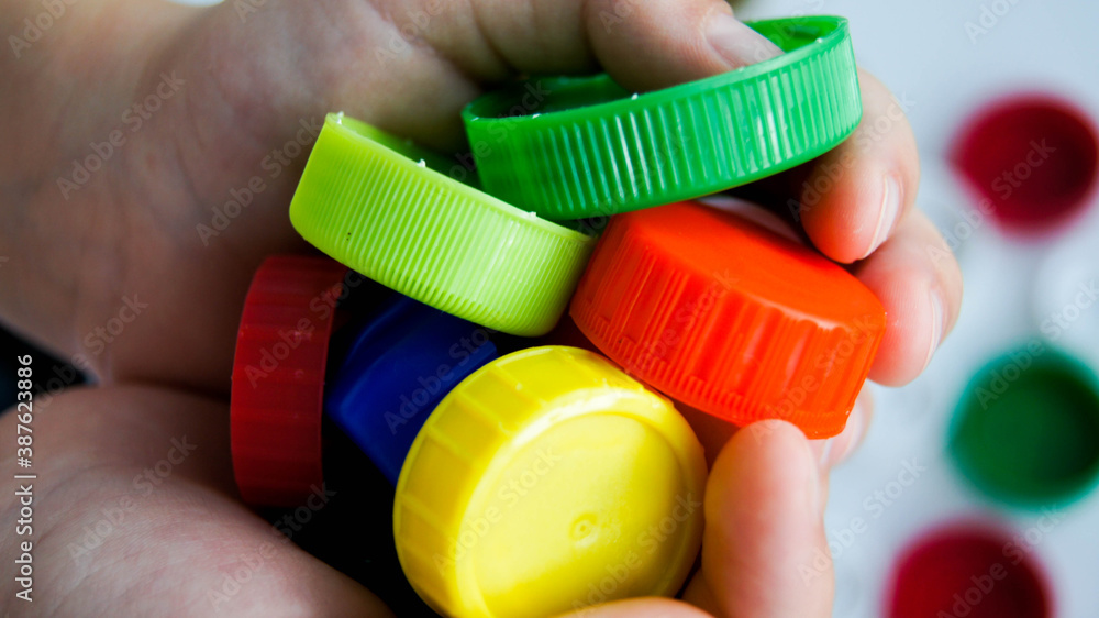 Childs hands holding colourful plastic bottles caps for recycling to ...