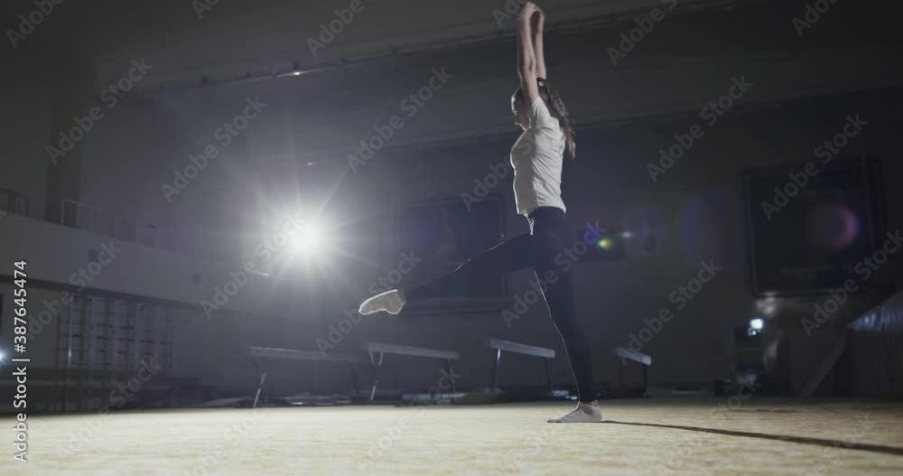 Low angle of flexible gymnastic girl doing side somersault in light of ...