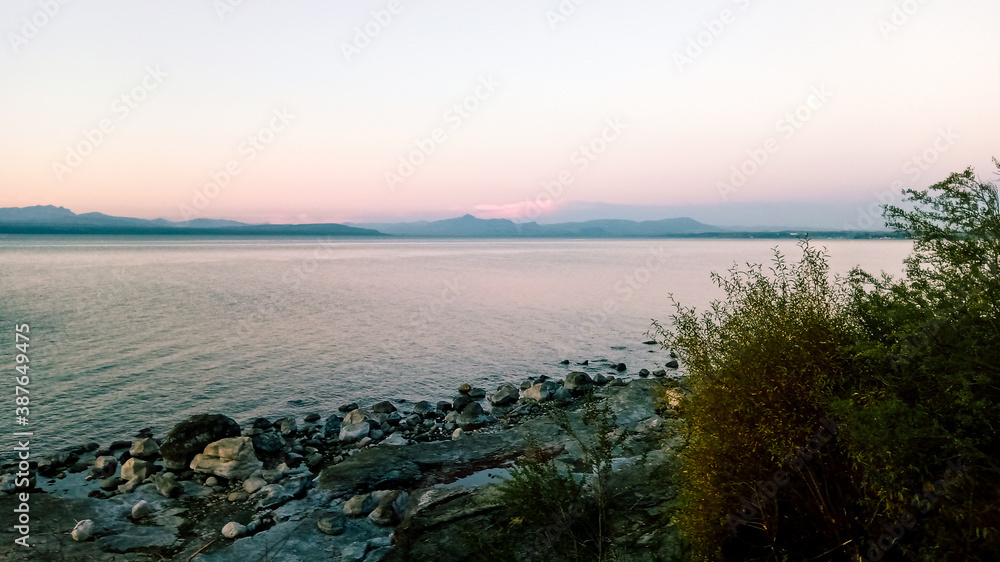 Foto de Vista de la costa rocosa de un lago junto a las montañas en un ...