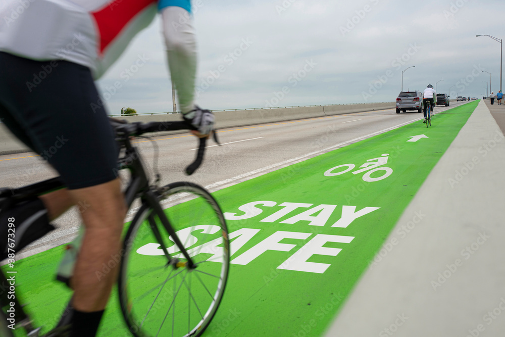 "STAY SAFE" - Man riding bike on street road at a designated green ...