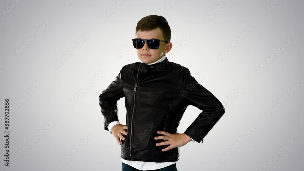 Young boy in a leather jacket putting on black glasses with arms on his ...