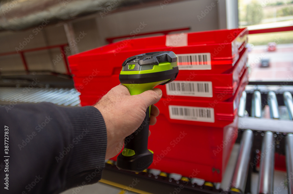 man holds a scanner and scans a barcode on a plastic box Stock 写真 ...