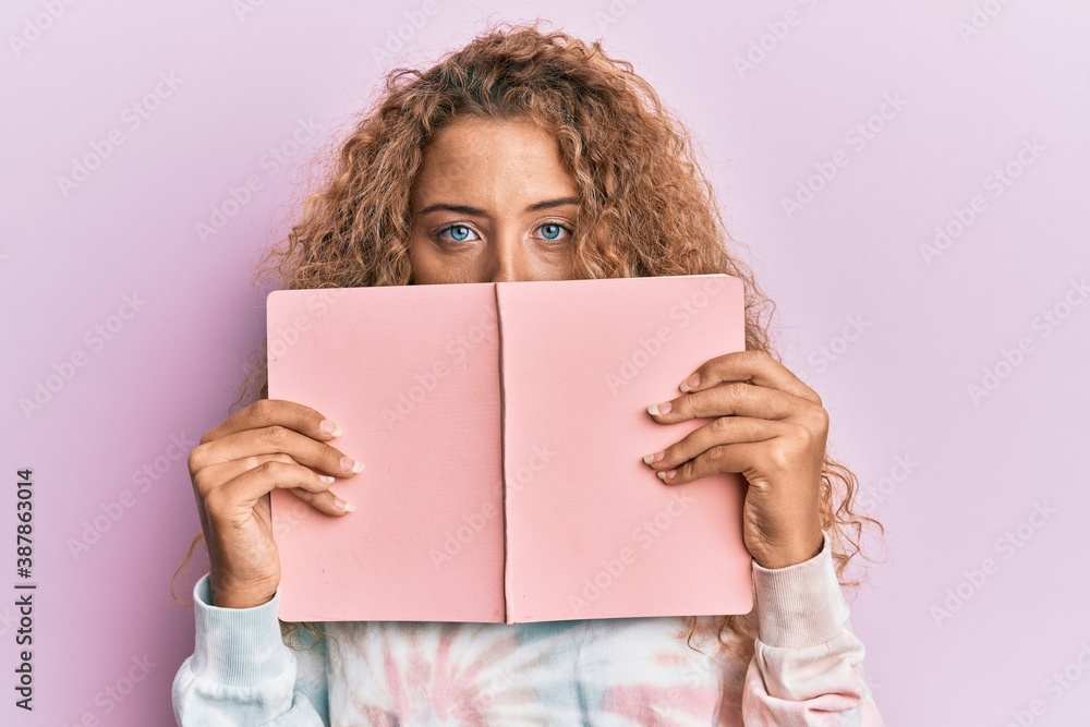 Beautiful caucasian teenager girl reading a book covering face ...