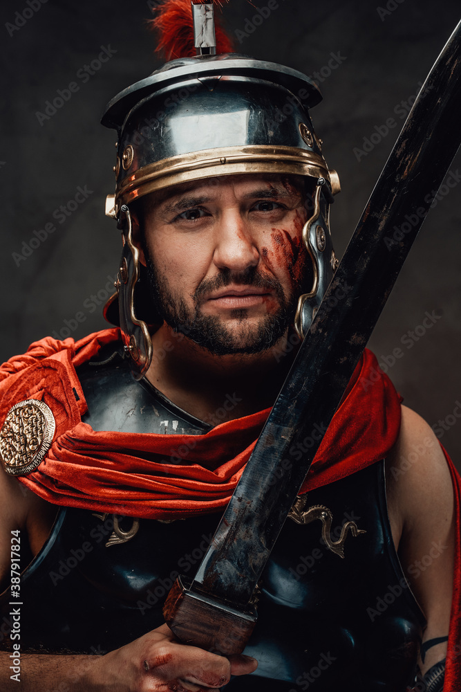 Warlike armoured roman warrior with red mantle posing holding his sword ...
