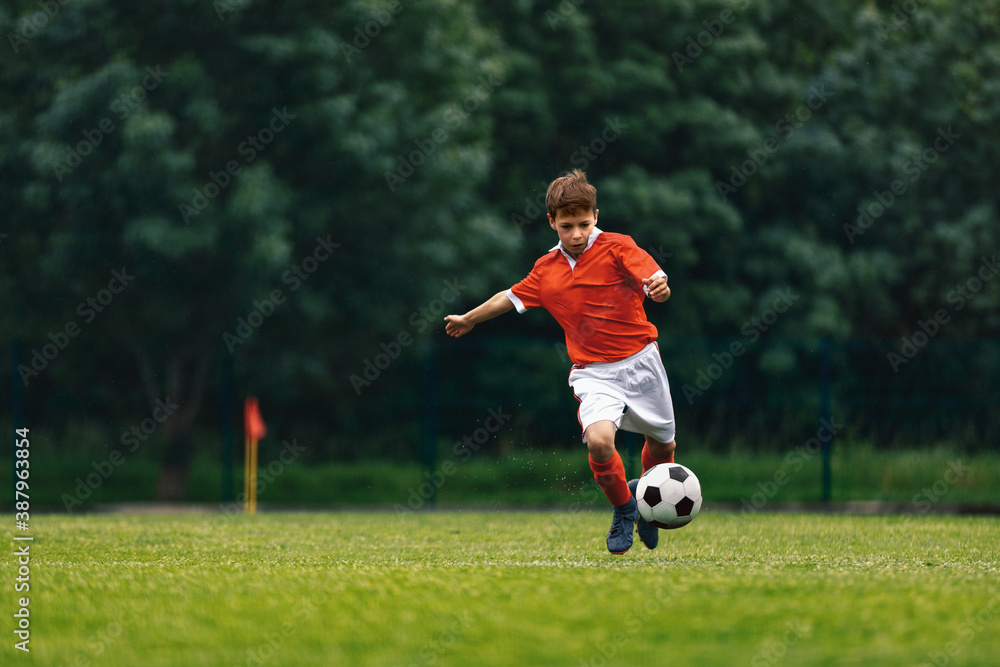 Soccer shooting. Boy kicking soccer ball on grass field. Young football ...