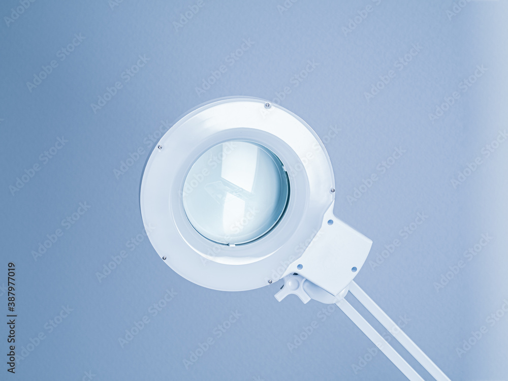 Round small white medical operating lamp in doctor's office. Light blue ...