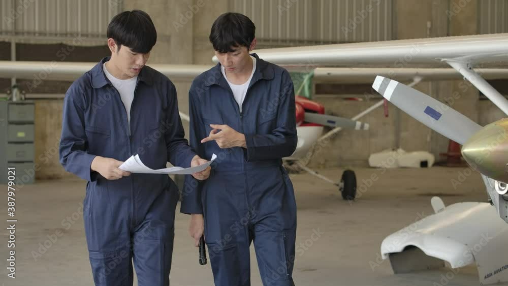 Two asian aviation engineers waking through airplane maintenance ...