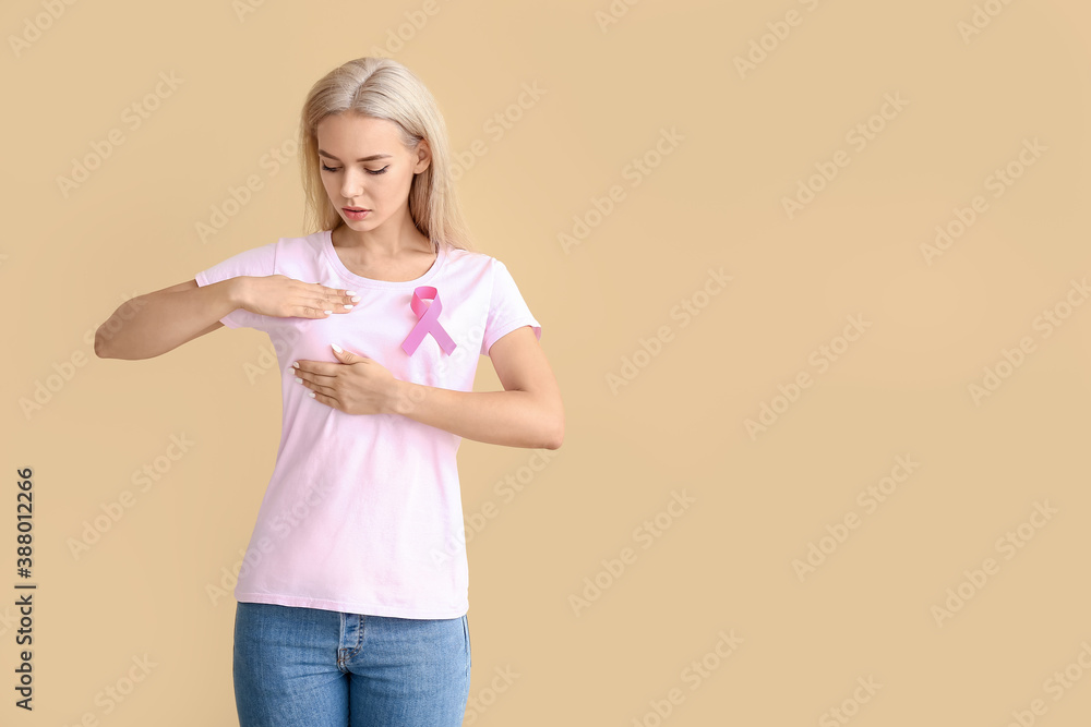 Young woman checking her breast on color background. Cancer awareness ...