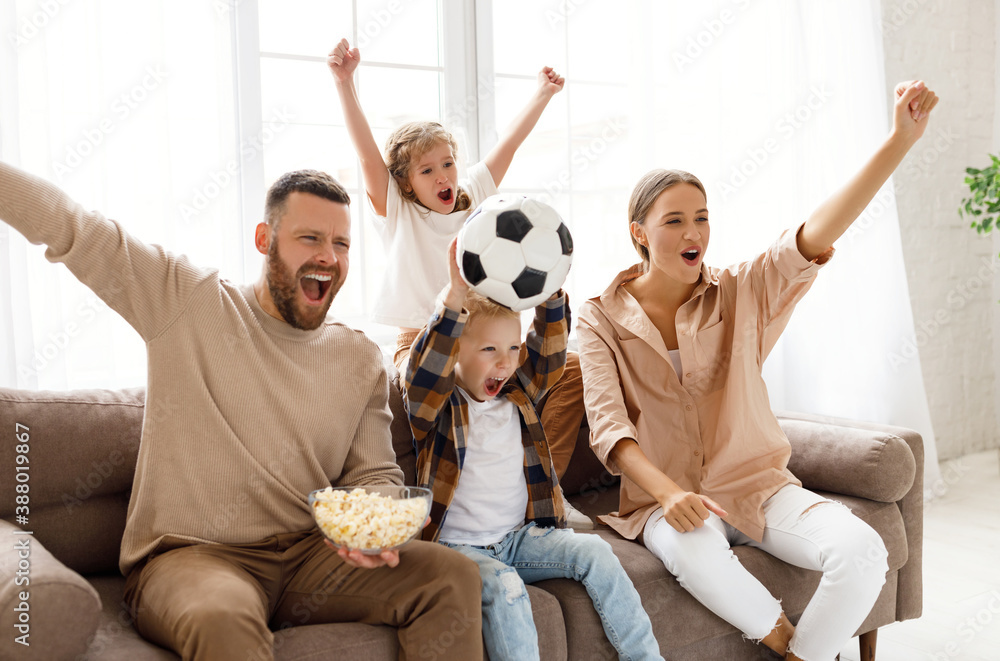 Excited family watching football at home. Stock Photo | Adobe Stock