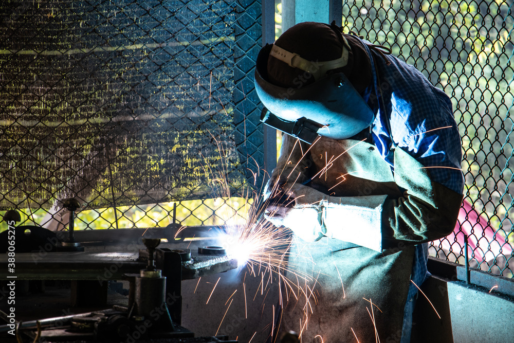 Profesional welder man in protective uniform with safety mask welding ...