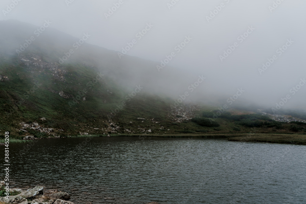 Mountain lake full of fog in rainy day. Windy and storm weather in the ...