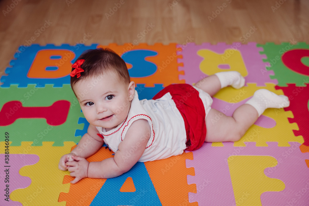 Cute smiling baby girl lying on colorful puzzle playmat at home Stock ...