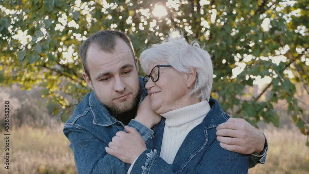 a young man hugs a loving 70s grandmother, expressing love and care ...