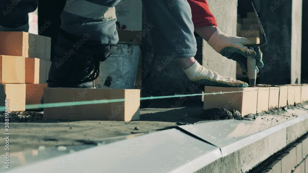 Bricks are getting laid on fresh cement by a worker. Construction ...