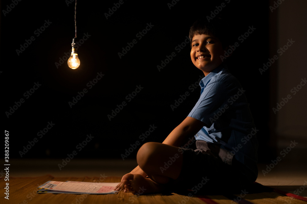 PORTRAIT OF A HAPPY BOY SITTING UNDER BULB LIGHT AND STUDYING Stock ...