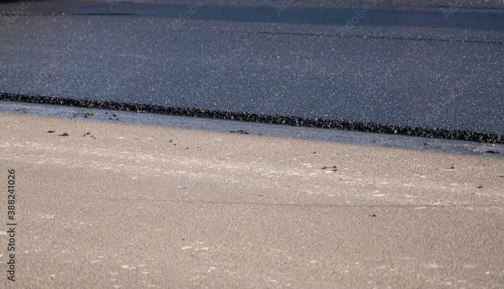 Freshly laid black bitumen asphalt with a high edge to the gravel ...
