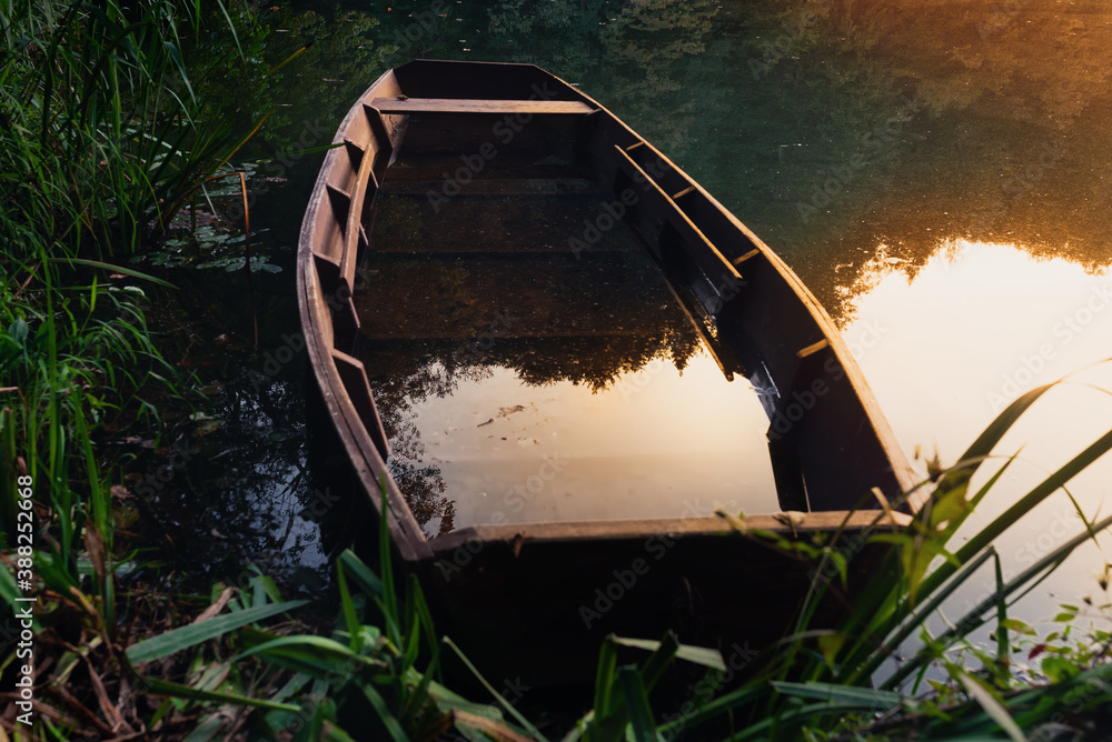 Submerged old wooden boat in sunset golden light, lake water surrounded ...