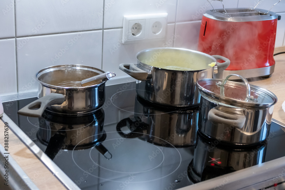 Cooking on cooker in the kitchen with hot steam and pots on a ceran ...