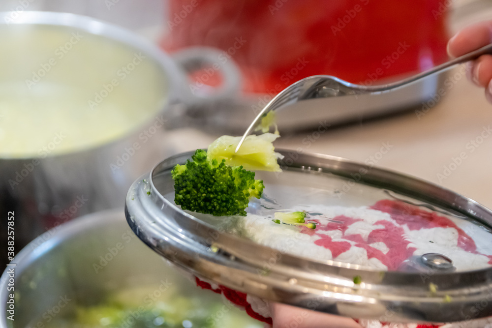 Woman cooking on cooker in the kitchen with hot steam and pots on a ...