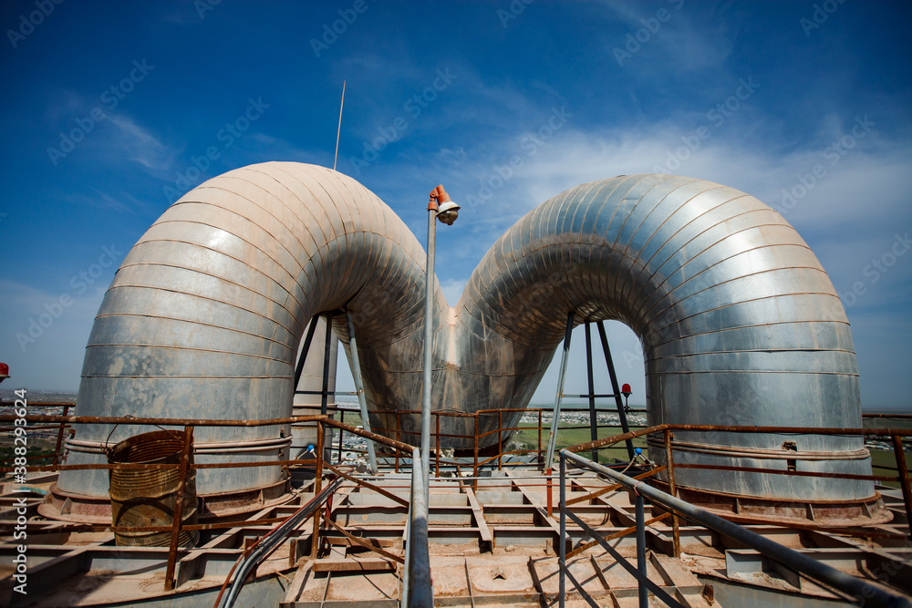 Metal tubes and safety red light on mast. Standard Cement plant. Blue ...