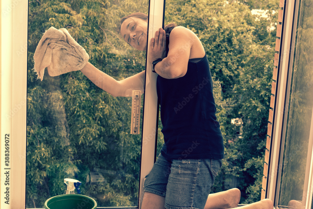 Back view of the young woman who washing the window with rag and window ...