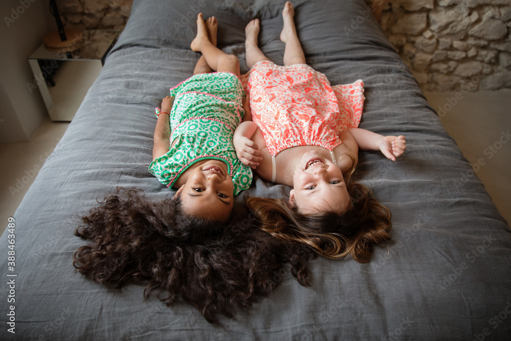 Smiling young girls lying upside down on bed Stock Photo | Adobe Stock