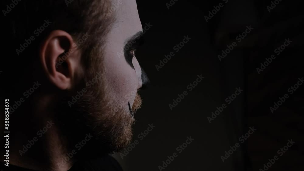 A man in zombie makeup, with a beard and black clothes comes out of the ...