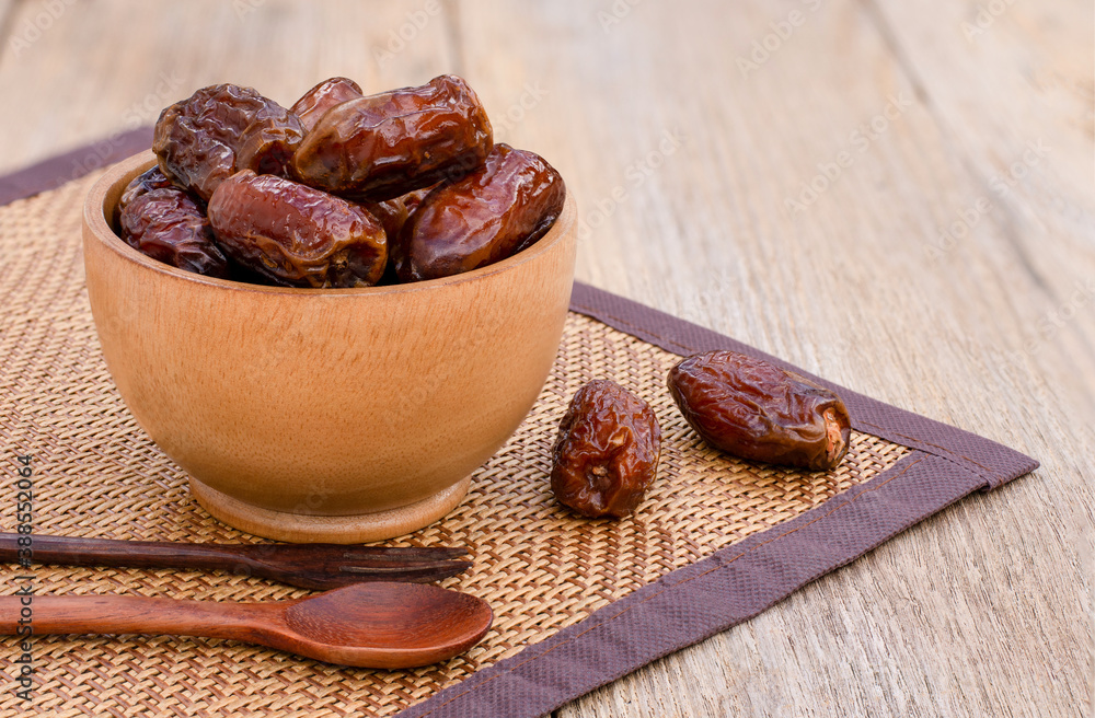 Closeup date palm fruits in wooden bowl isolated on wood table ...