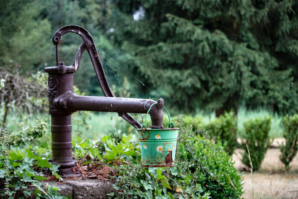 Very old well with small green bucket. Stock Photo | Adobe Stock