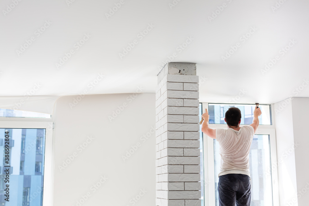 repairmen install stretch ceiling made of pvc vinyl film using a gas ...