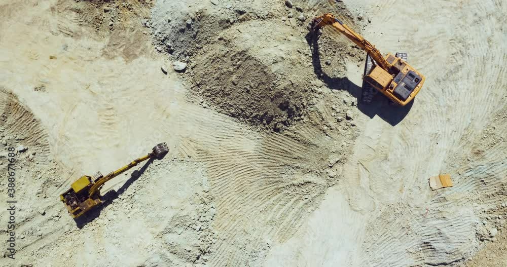 Aerial top view, orange excavator with truck working in quarries site ...