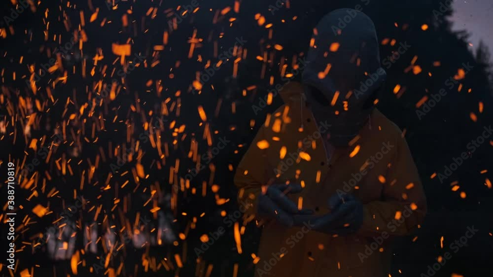 alien sitting in a yellow suit by fire, evening in nature, sparks of ...