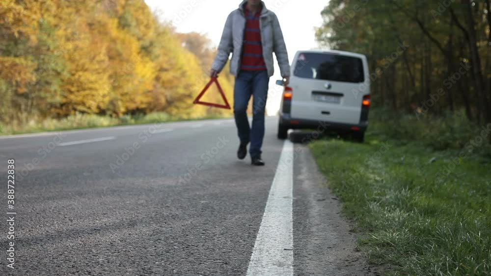 A male driver places an emergency stop sign on the road. Minibus with ...