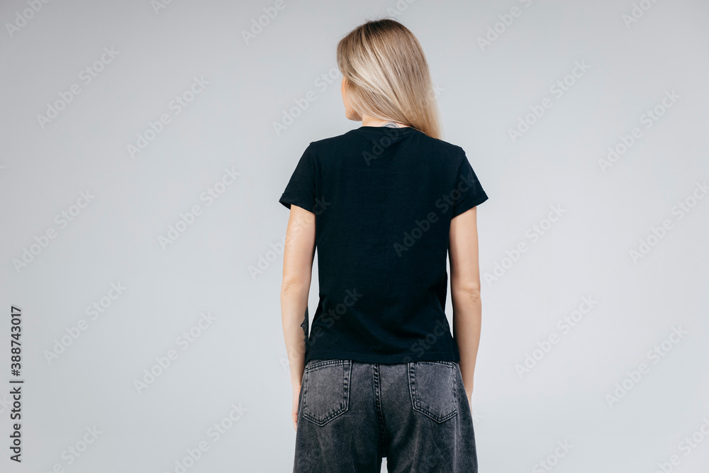 Back of stylish blonde girl wearing black t-shirt posing in studio ...