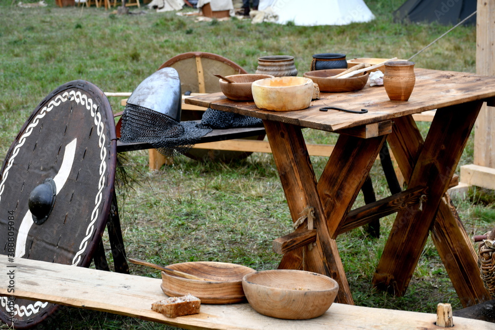 Close up on an old wooden table with some pots, cups, and mugs laying ...