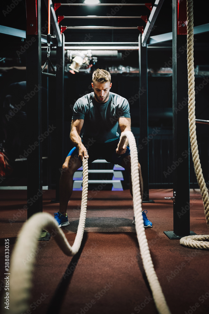 Fit man working out with battle ropes at fitness gym Stock Photo ...