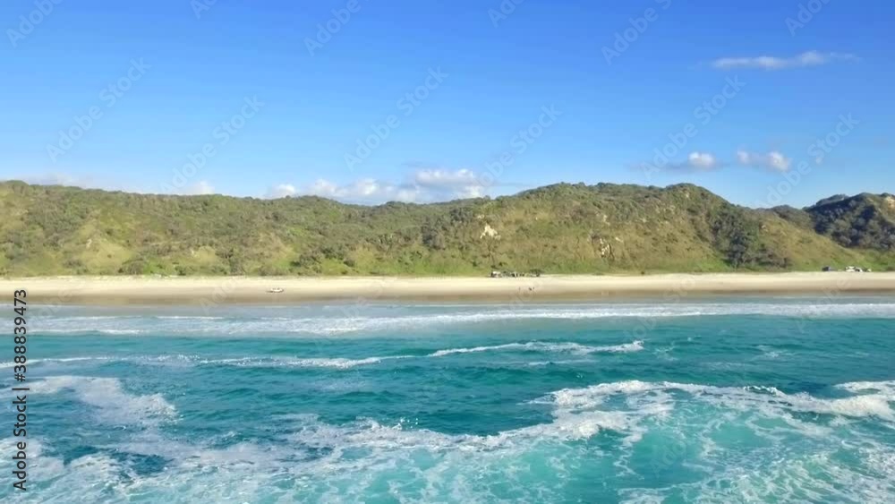 Smooth drone shot flying over the foamy waves and back towards the ...