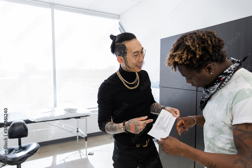 Tattoo artist giving written advice to customer in studio Stock Photo ...