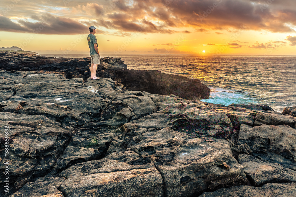 Man standing on basalt rocks from an ancient lava flow by the edge of ...