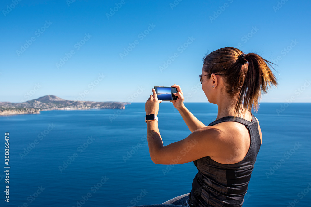 Woman taking pictures with her smartphone to the landscape, in nature ...