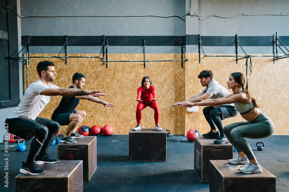 Group of athletes doing squats on cubes during training Stock Photo ...