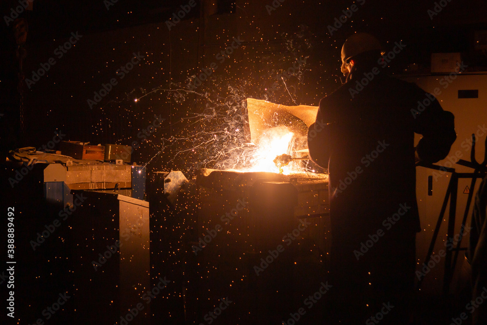steelworker removing slag from steel furnace with sparks and smoke ...