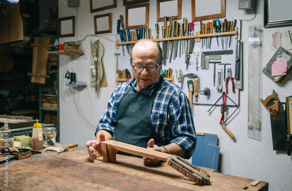 Luthier making fretboard of guitar while standing at workshop Stock ...