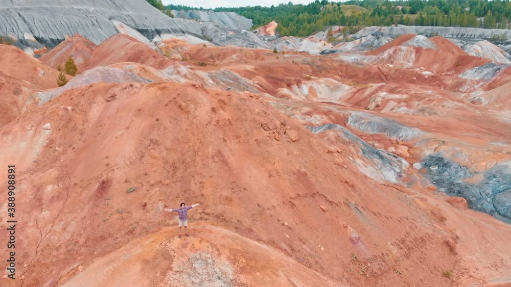 A man running on a clay mountain and raising his hands up - landscape ...
