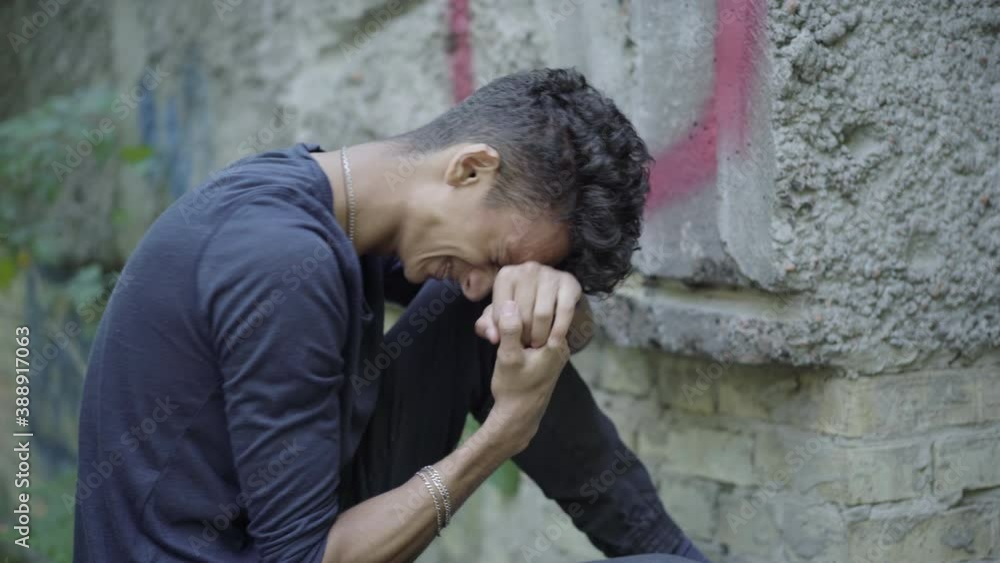 Desperate lonely young man punching wall with fist and crying. Side ...