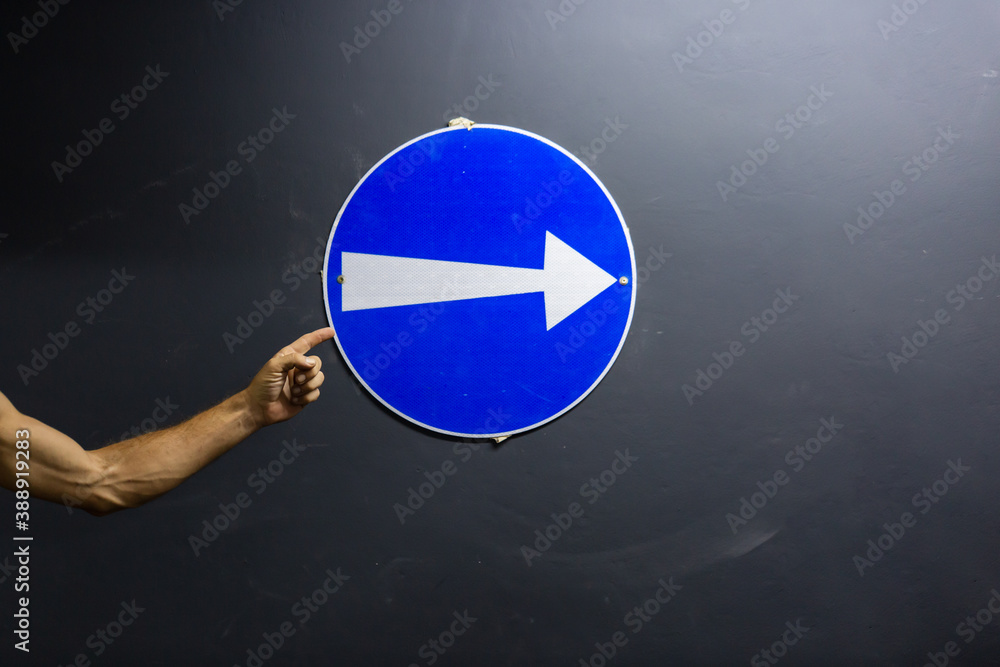 The hand points to the blue sign with arrow, round blue sign with arrow ...