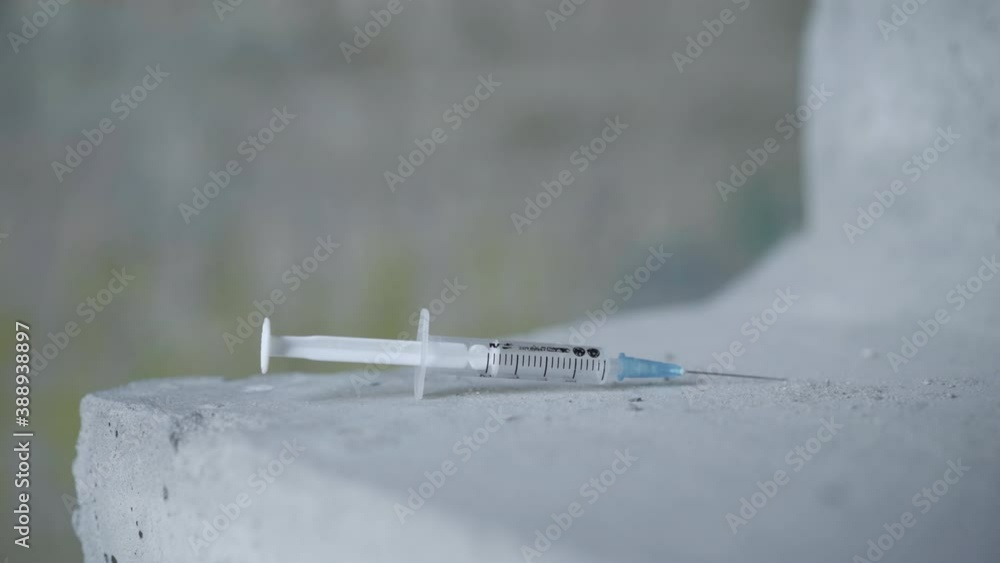 Close-up of male hand putting syringe on brick in ruins. Unrecognizable ...